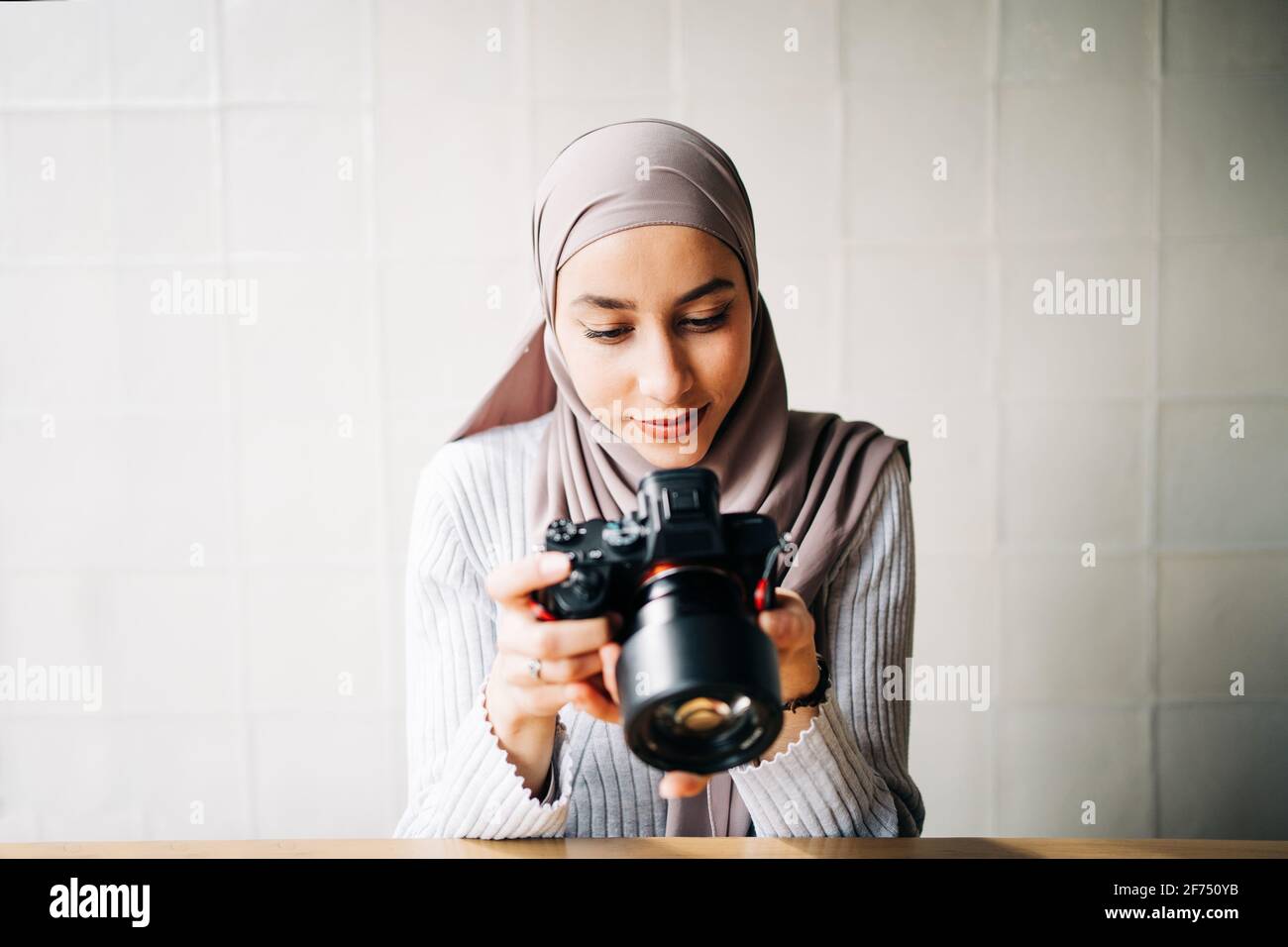 Focused Muslim female photographer sitting at table and looking through ...