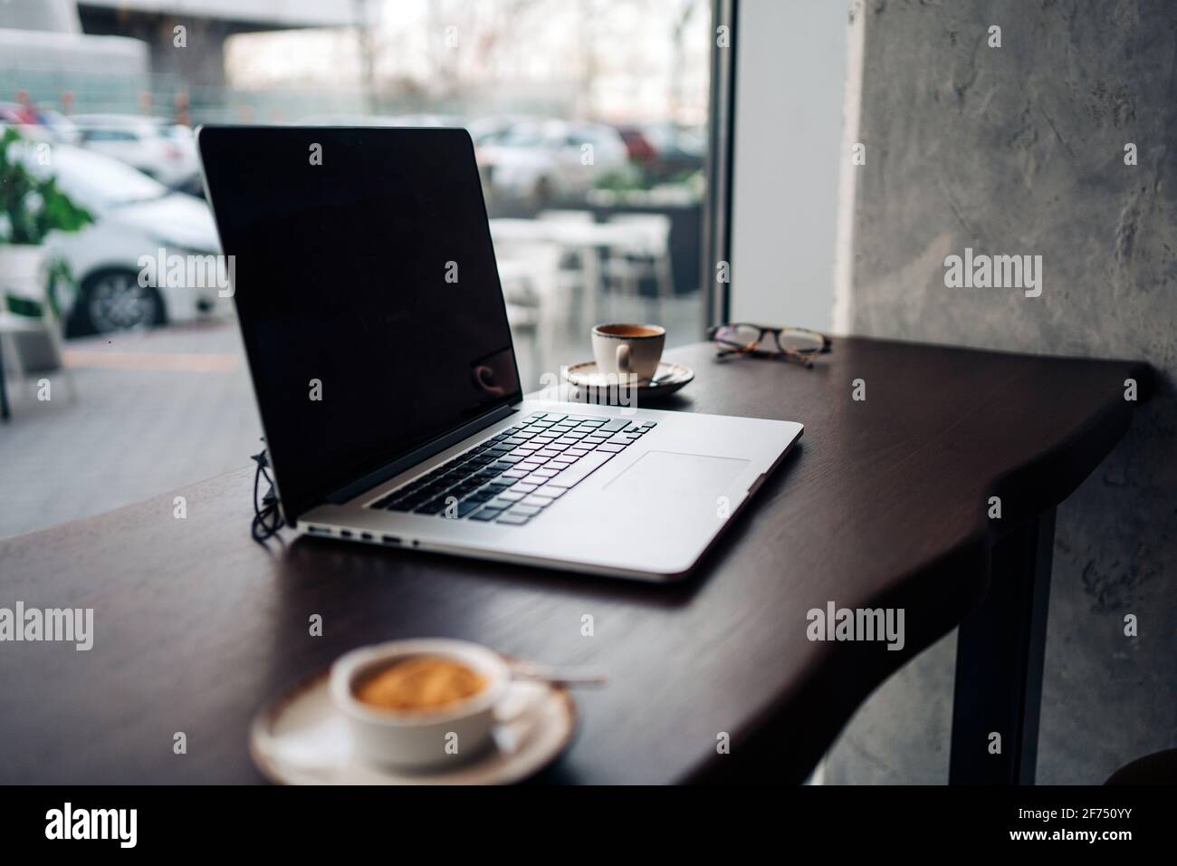 Modern netbook with black screen on wooden table with cups of aromatic ...