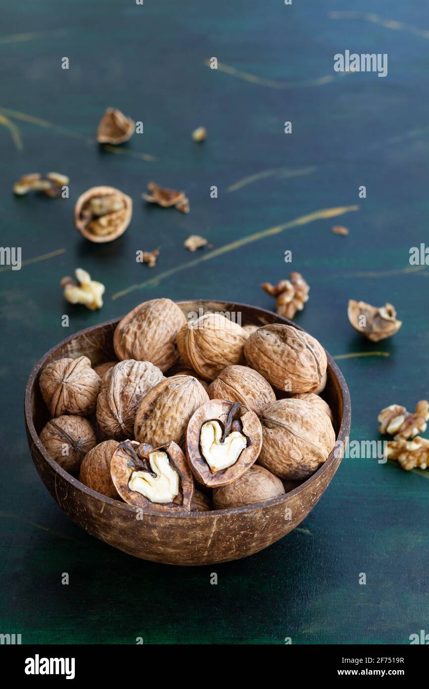 Round shaped wooden bowl full of crunchy walnuts with dry uneven ...