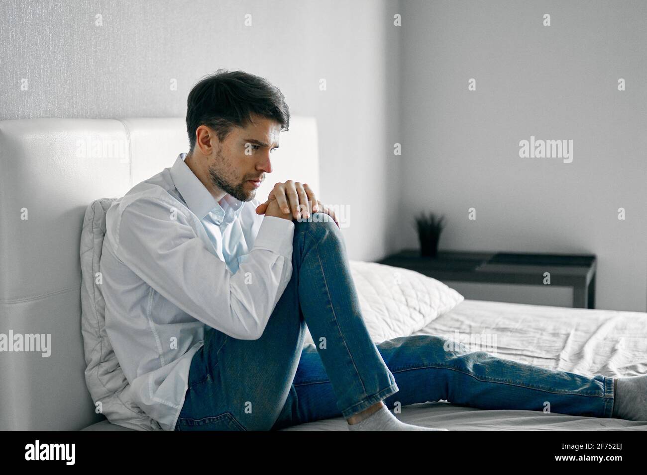 lonely man sitting on sofa indoors puzzled look Stock Photo - Alamy