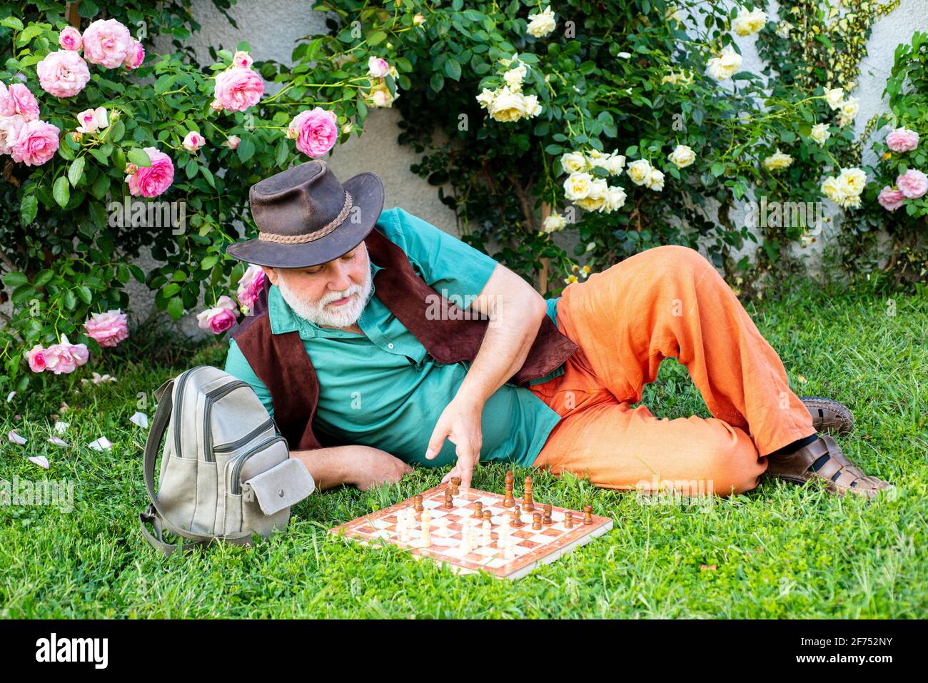 Old man in spring rosesgarden with chess. Hobby concept. Happy old age ...