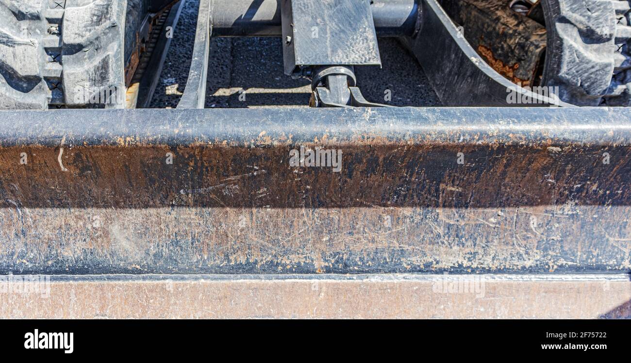 The dozer blade of an excavator, shows signs of heavy duty use over the ...