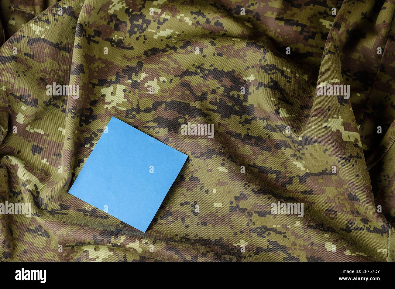 A fragment of a crumpled camouflage military uniform and a blue sheet ...
