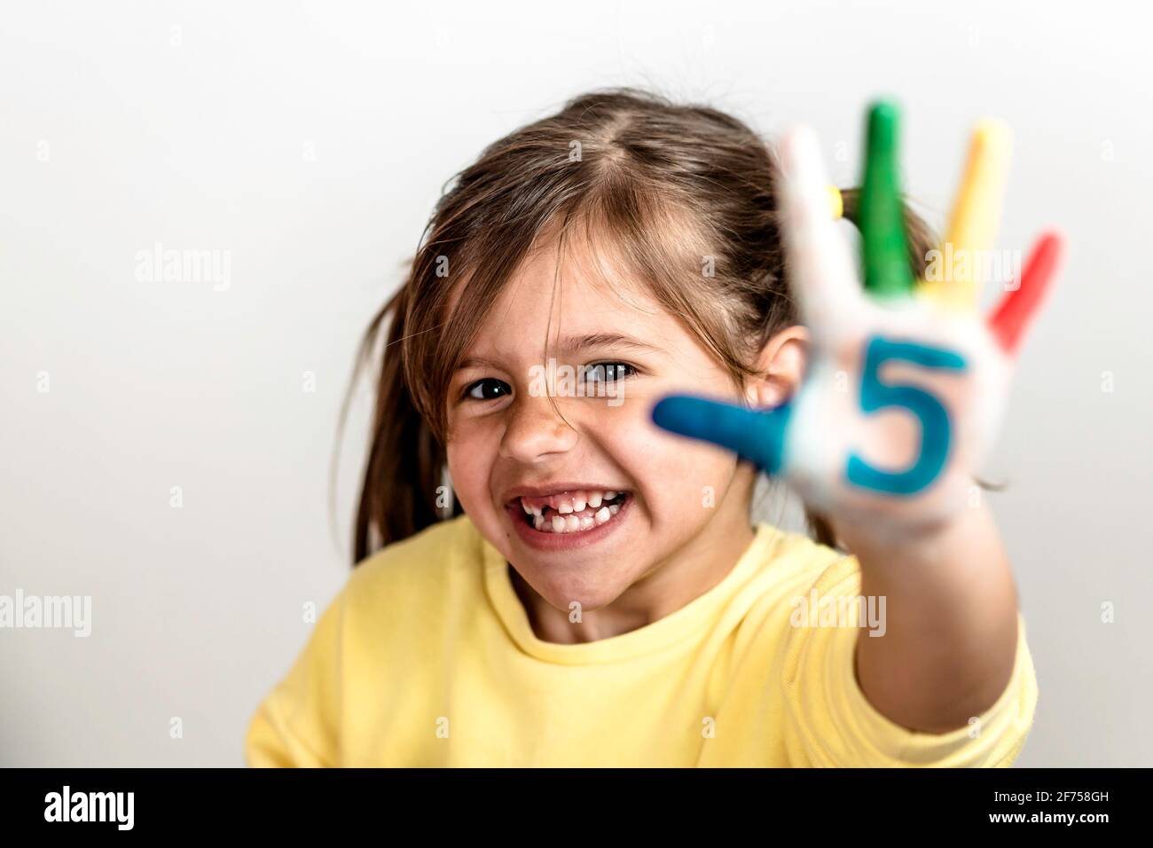 Happy toothless little girl with the five number painted on the hand ...