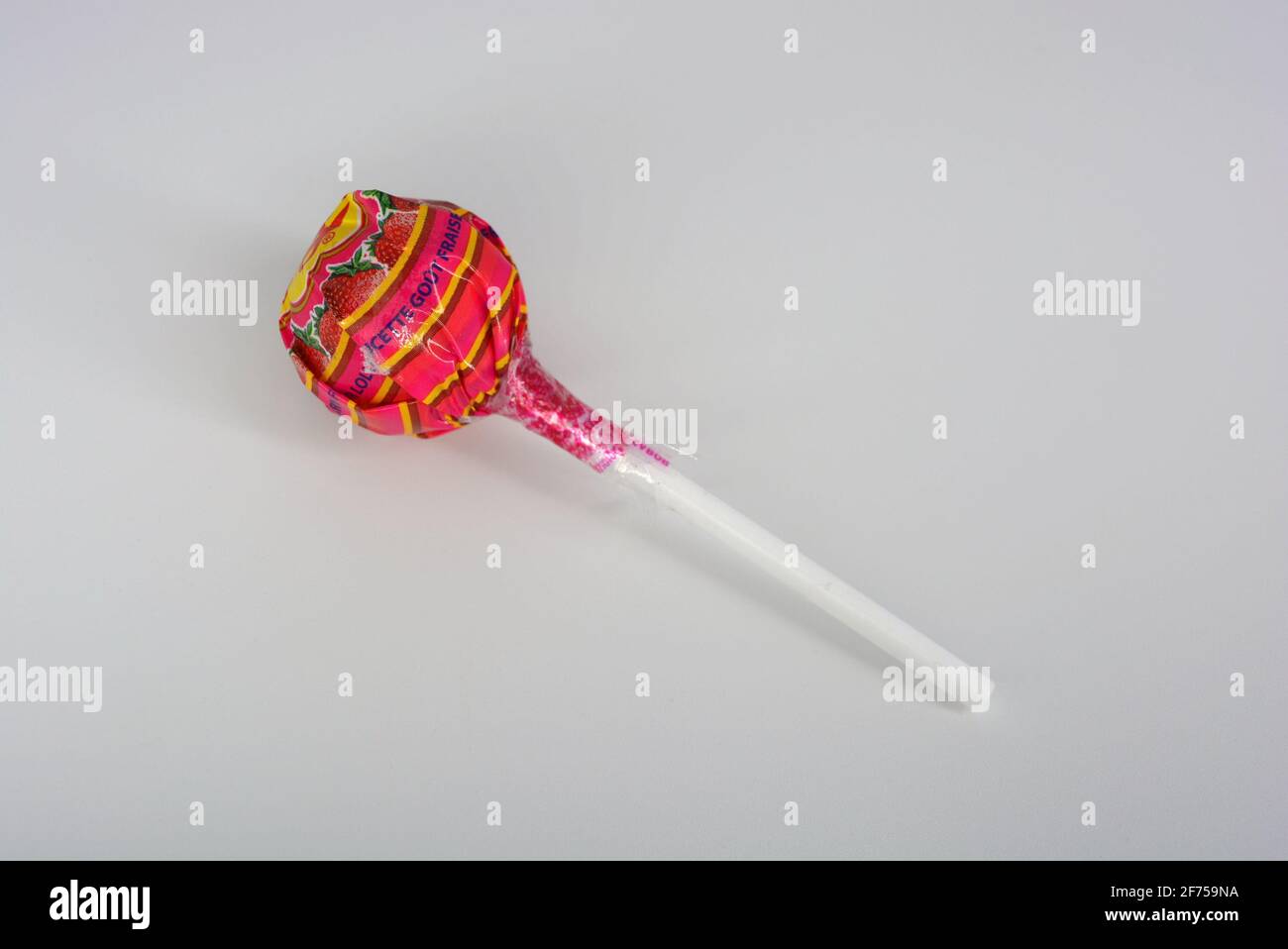 Delicious round sweet candy, white pink lollipop on white plastic stick ...