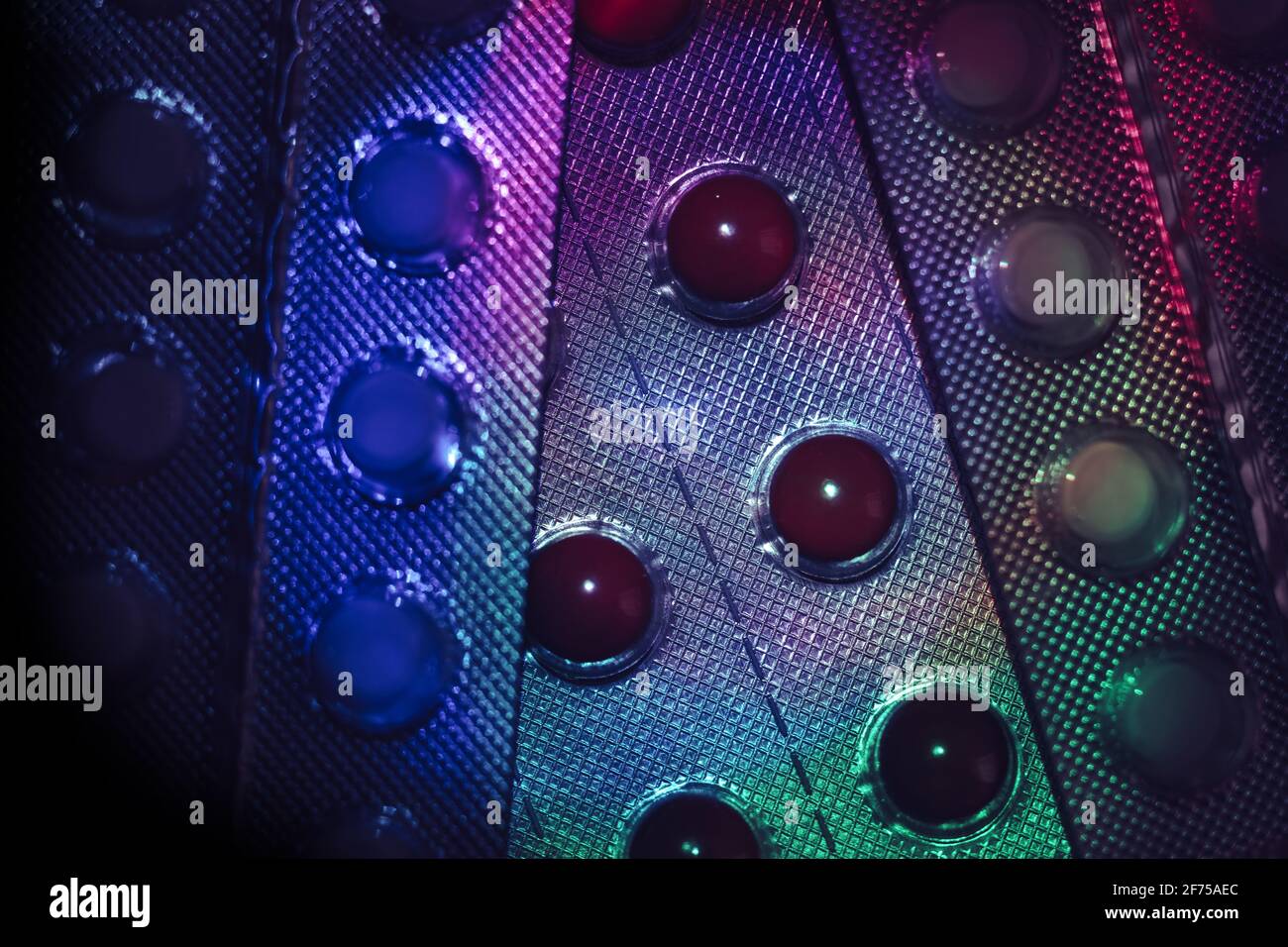 Pills or drugs in a package under neon light on a dark background ...
