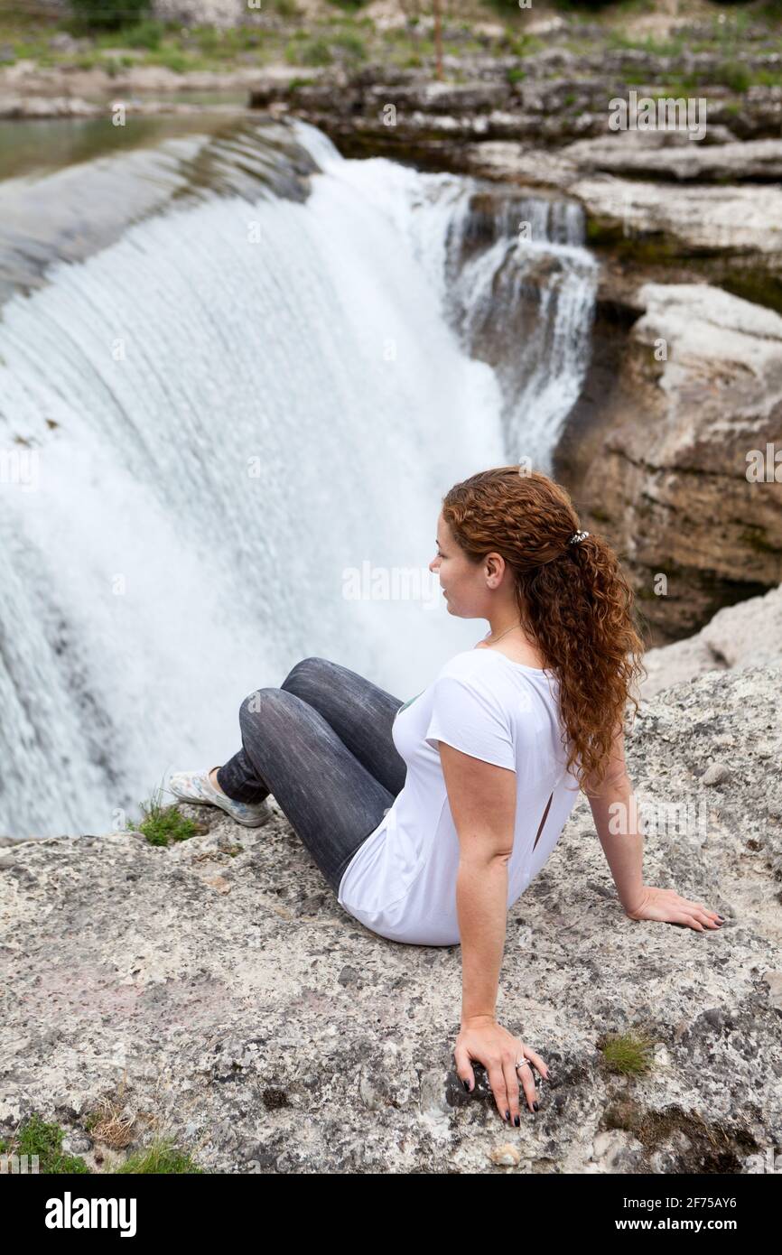 Pretty woman sitting on rock and enjoying of the cascade of Cijevna ...