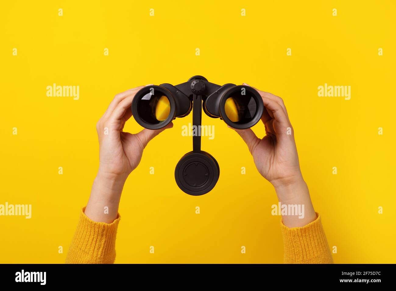 binoculars in hand over yellow background, search concept Stock Photo ...
