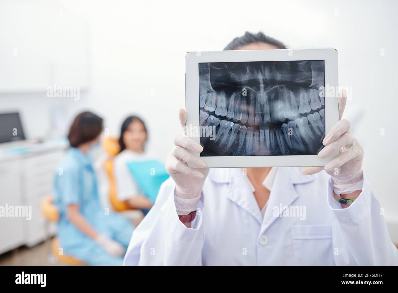Dentist showing tablet computer with jaw x-ray of female patient on ...