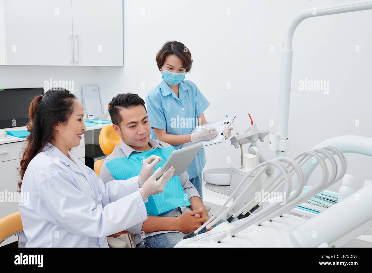 Smiling dentist showing tablet computer with teeth x-ray to patient and ...