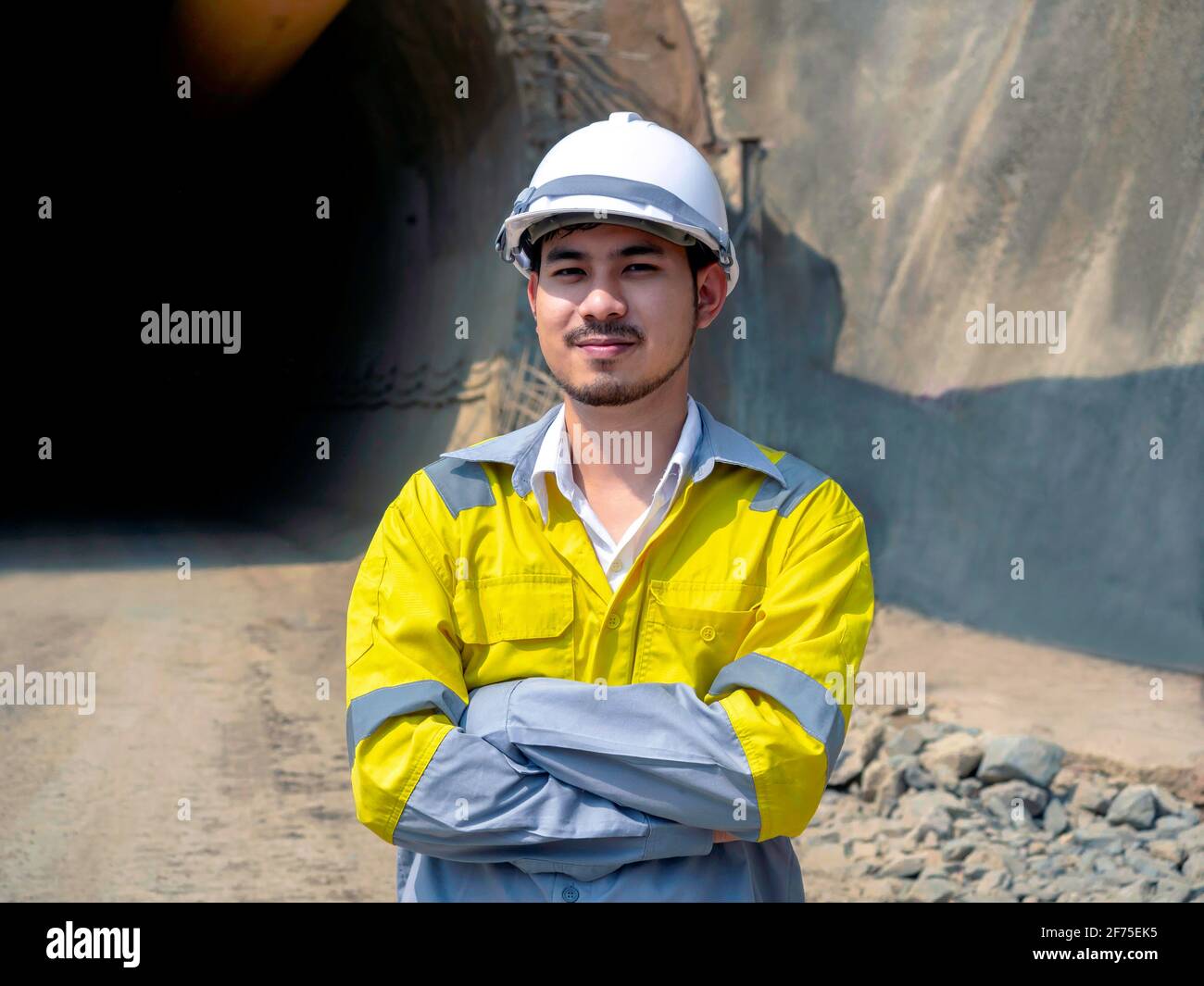 Portrait of young handsome Asian tunnel engineering wearing yellow high ...