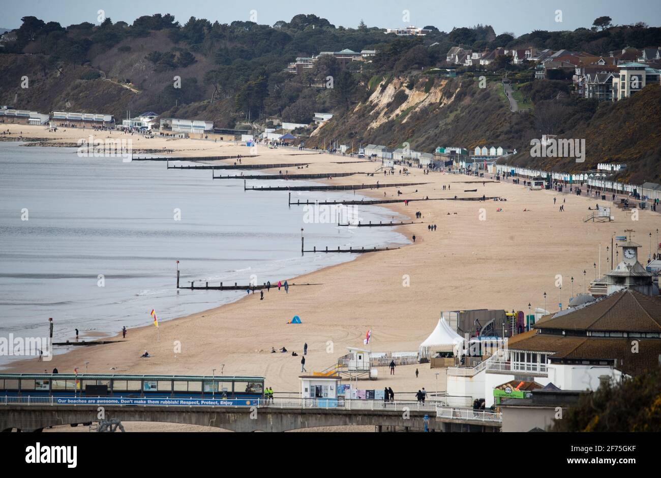 People make their way along a near deserted Bournemouth beach in Dorset ...