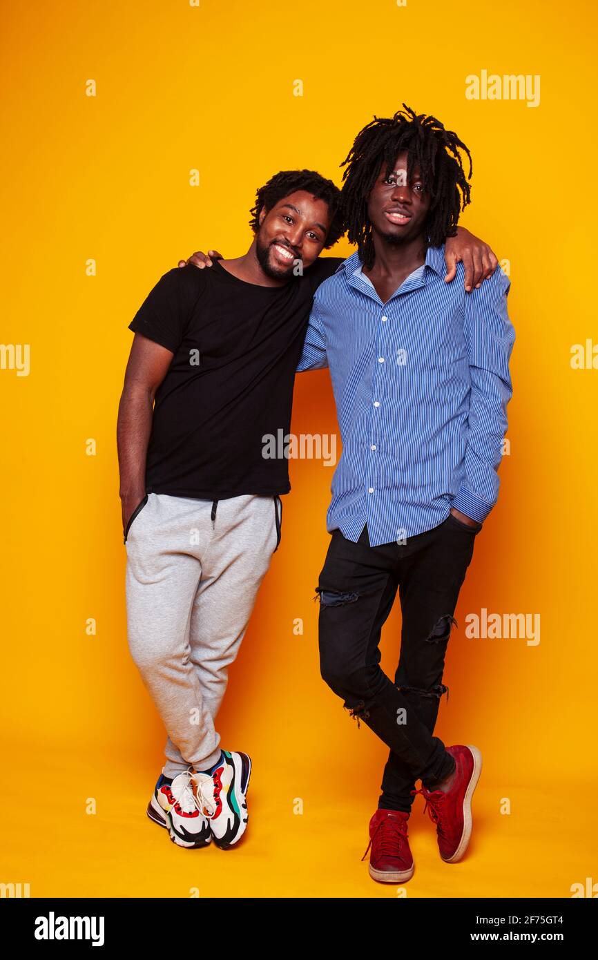 two african american guys posing cheerful together on yellow background ...