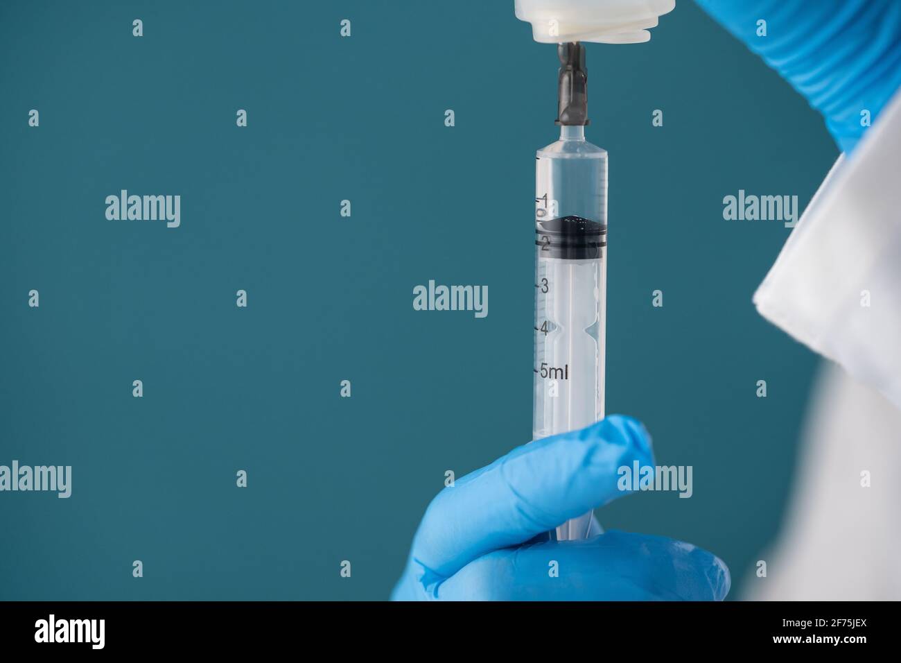 A nurse draws an antibiotic solution or vitamins from a clear vial with ...