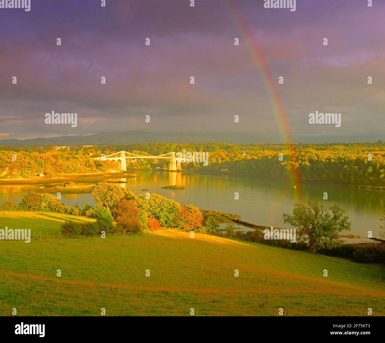 UK, Wales, Menai Bridge over Menai Strait, autumn, sunset, with rainbow ...