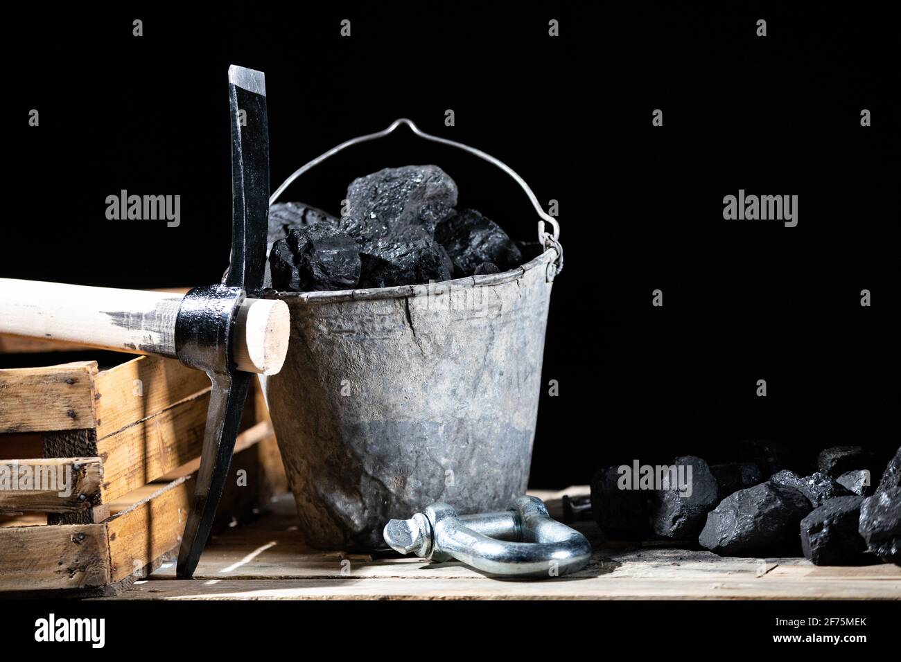Large pickaxe with wooden handle on black background with lumps of ...