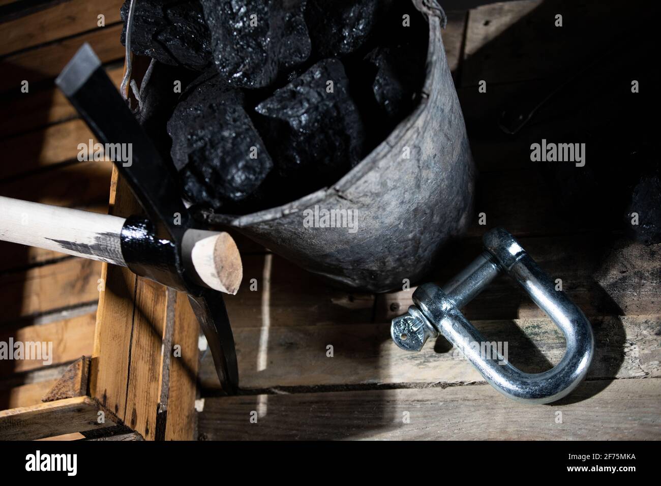 Large pickaxe with wooden handle on black background with lumps of ...