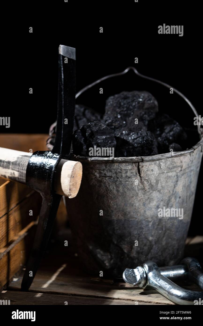 Large pickaxe with wooden handle on black background with lumps of ...