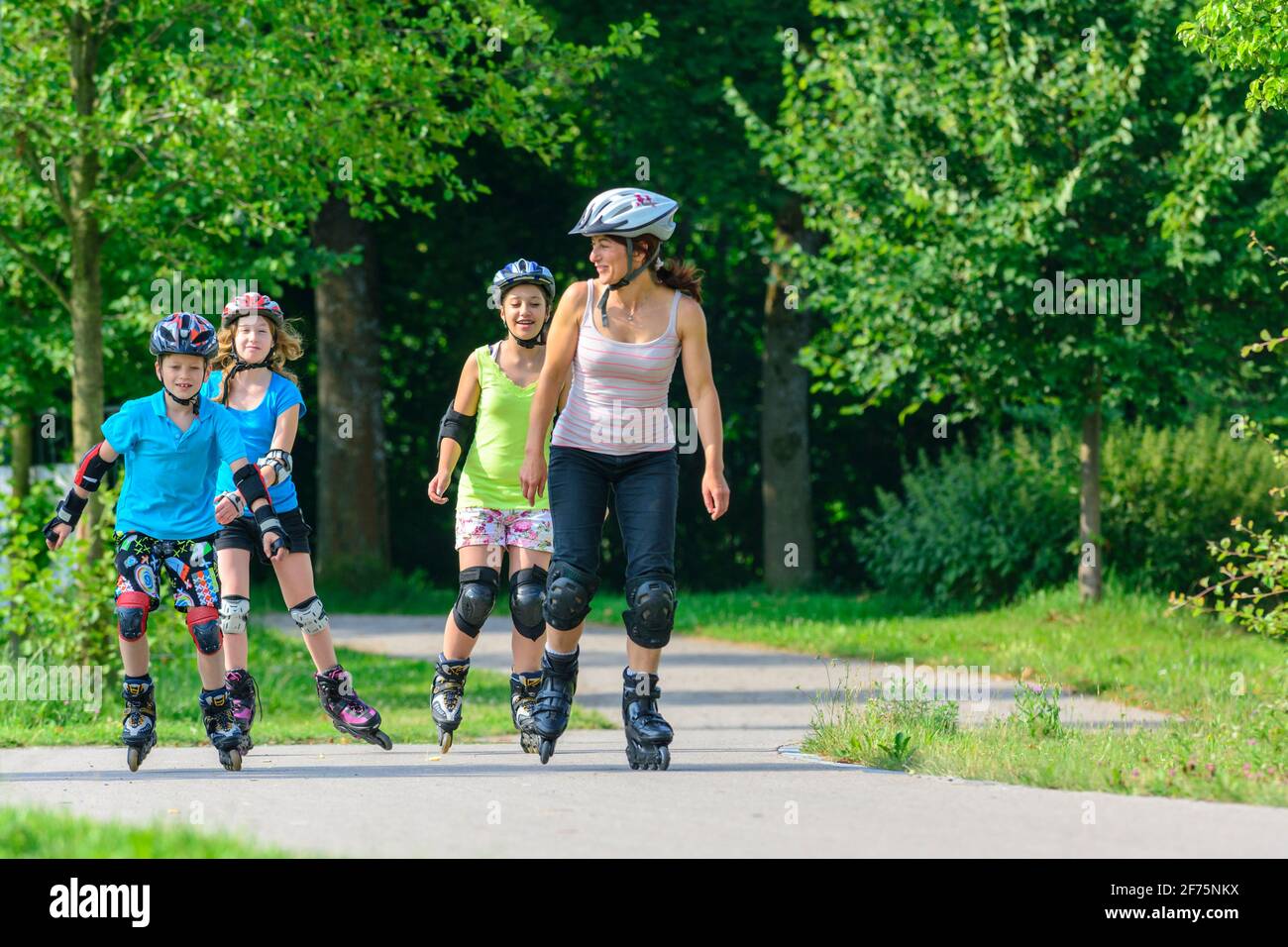Young family doing a tour on inline skates in urban park at a sunny ...