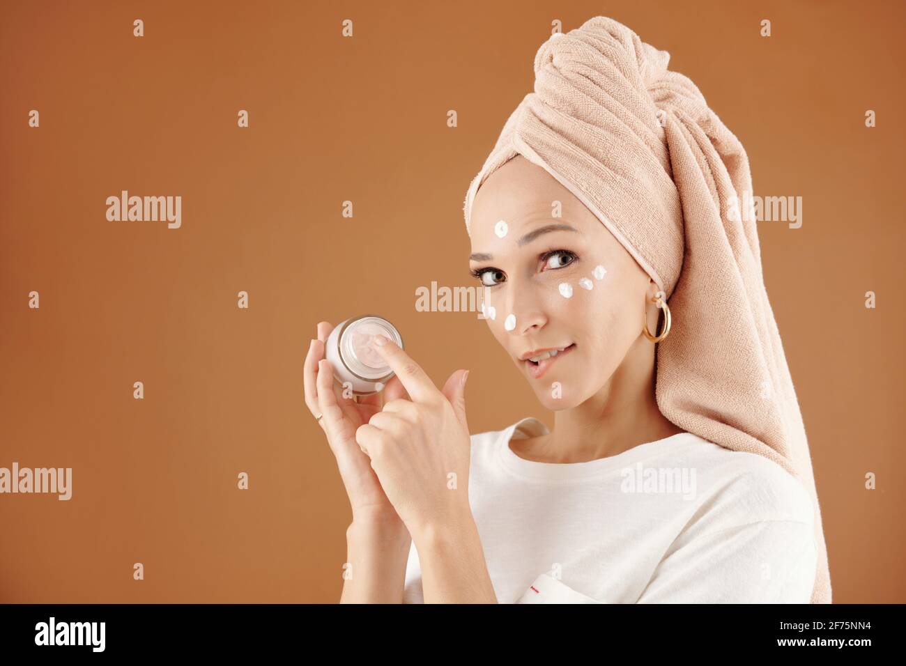 Beautiful young woman applying rejuvenating cream enriched with ...