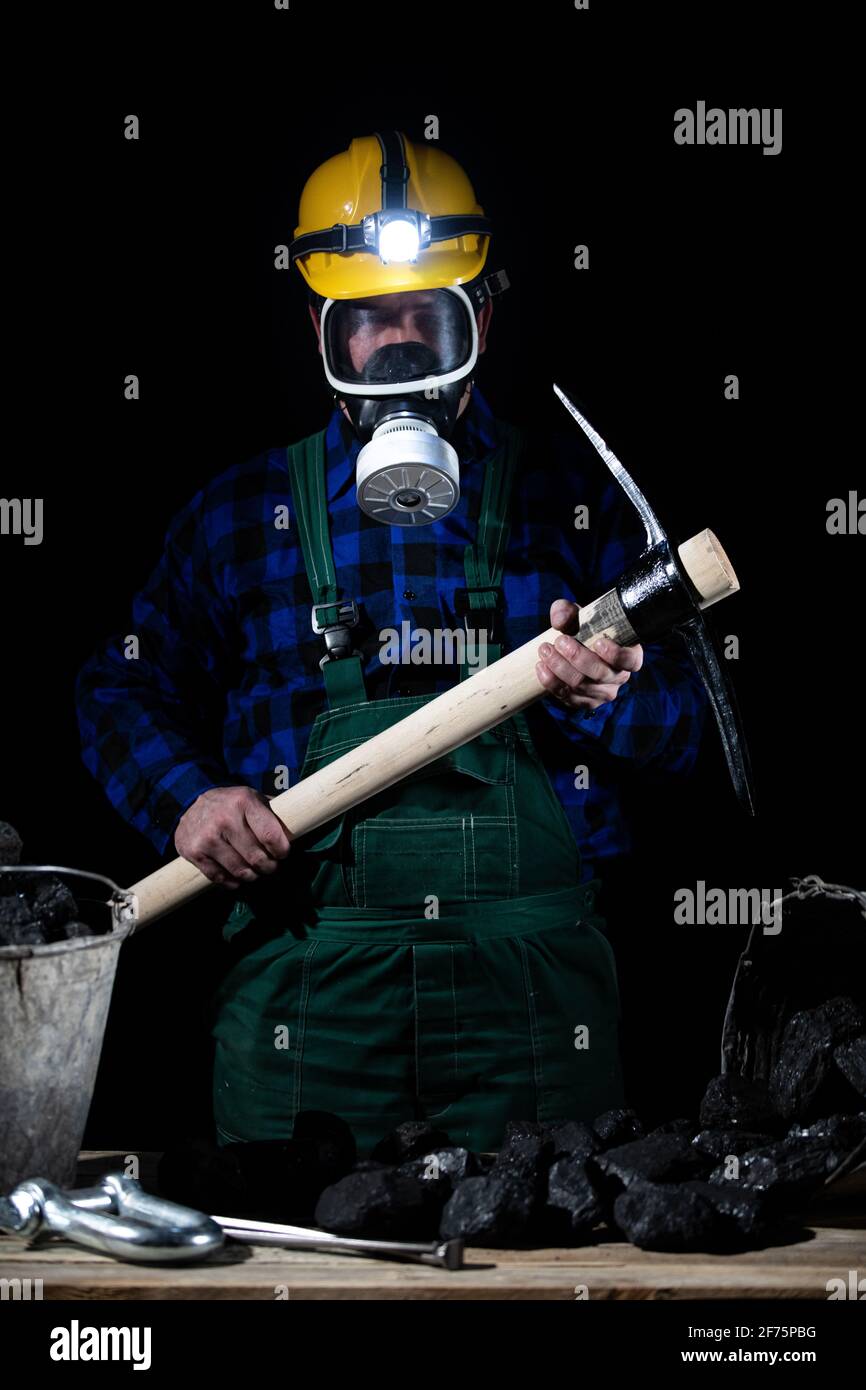 A miner with a protective helmet on and a flashlight and dust mask in ...