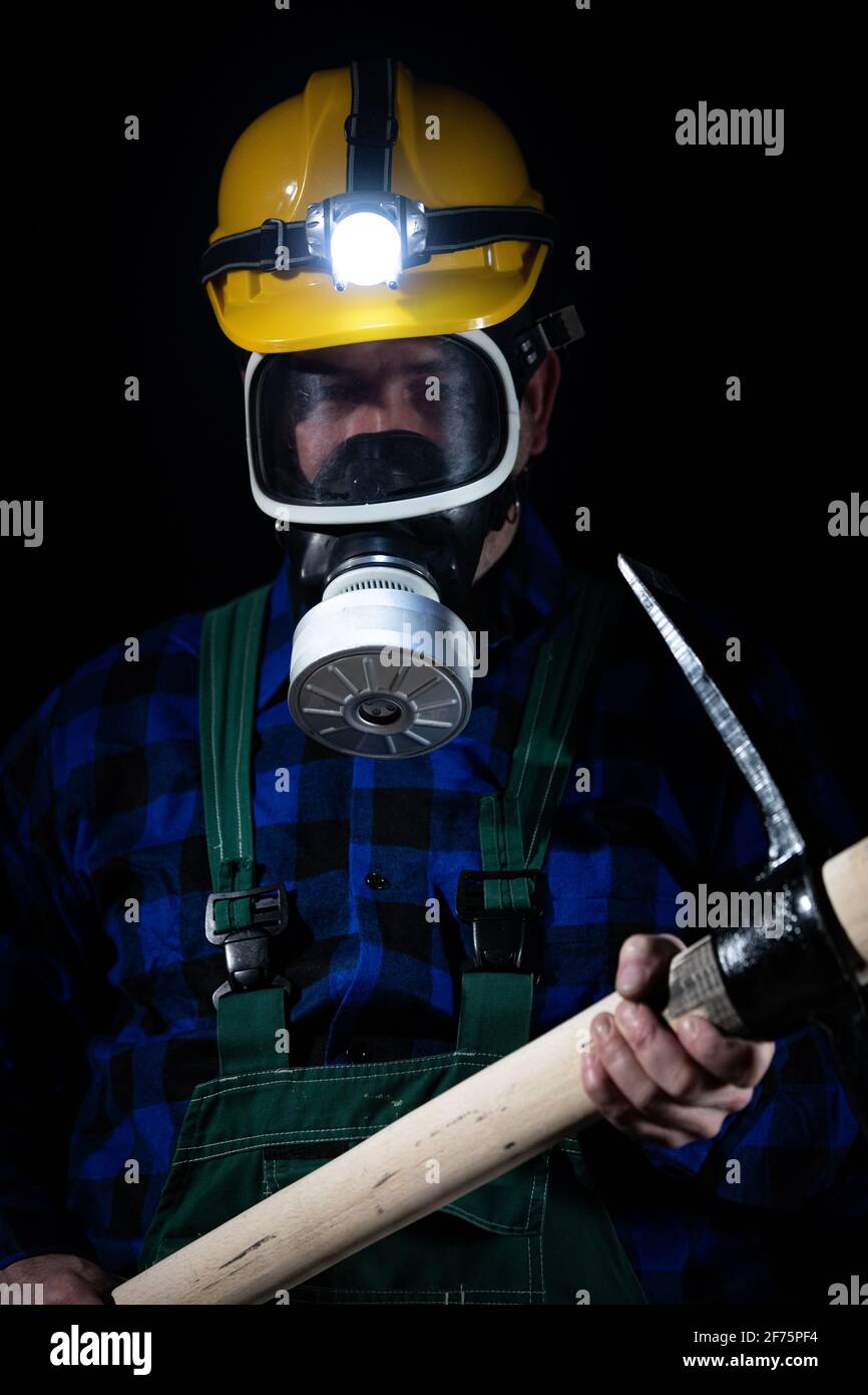 A miner with a protective helmet on and a flashlight and dust mask in ...