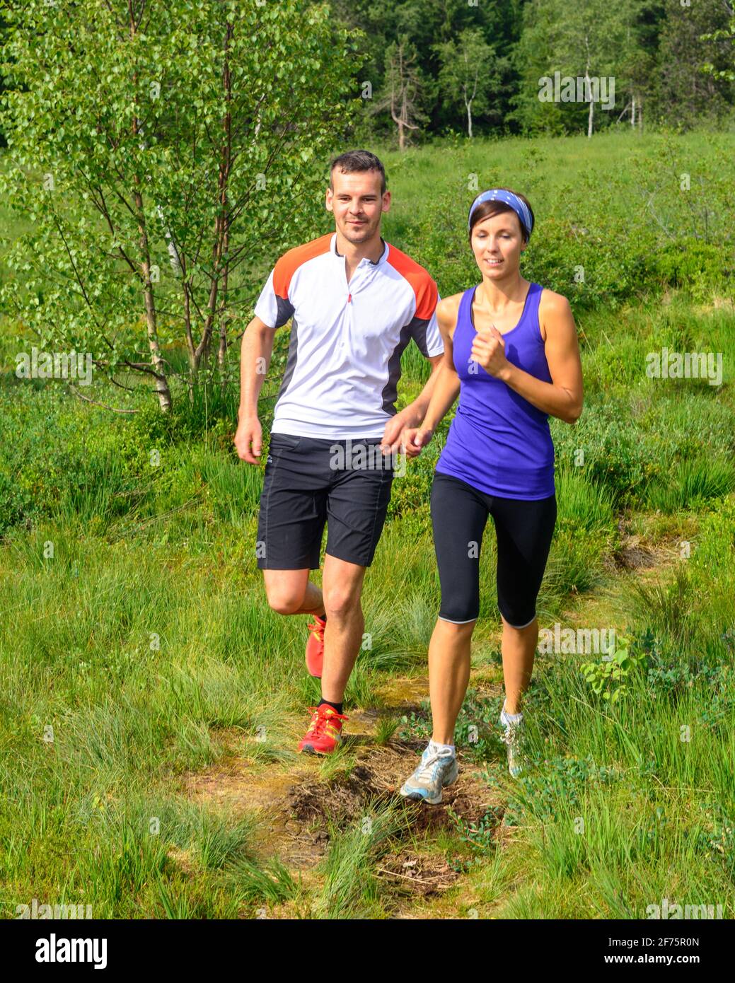 Young people jogging on a forest path, joint-friendly running training ...