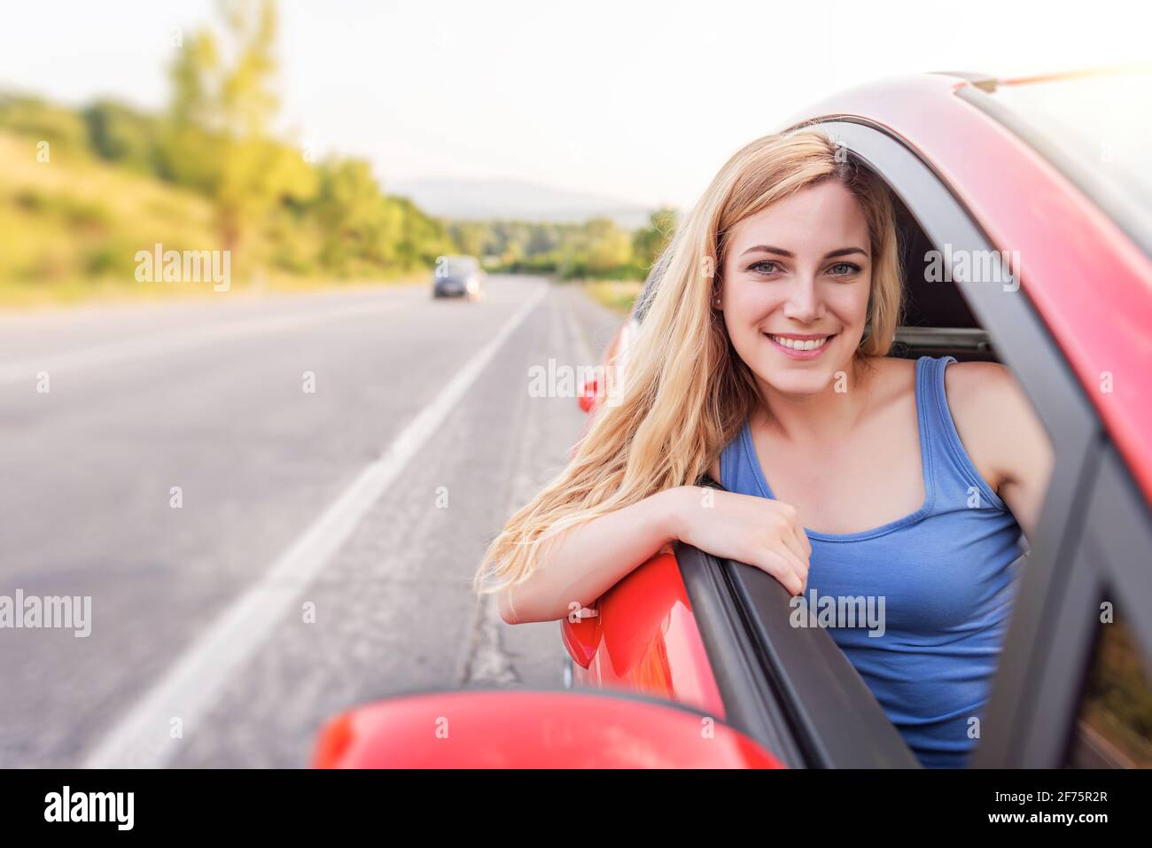 Happy beautiful woman is driving a red car Stock Photo - Alamy