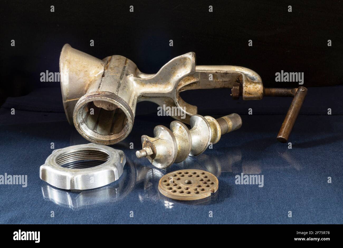 An old meat grinder on a glass table with a reflection. Kitchen ...