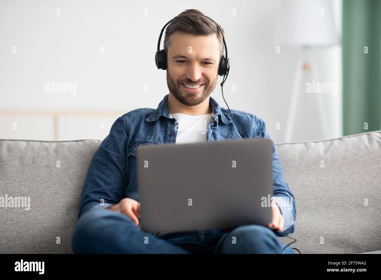 Relaxed man watching movie, using laptop and headphones Stock Photo - Alamy