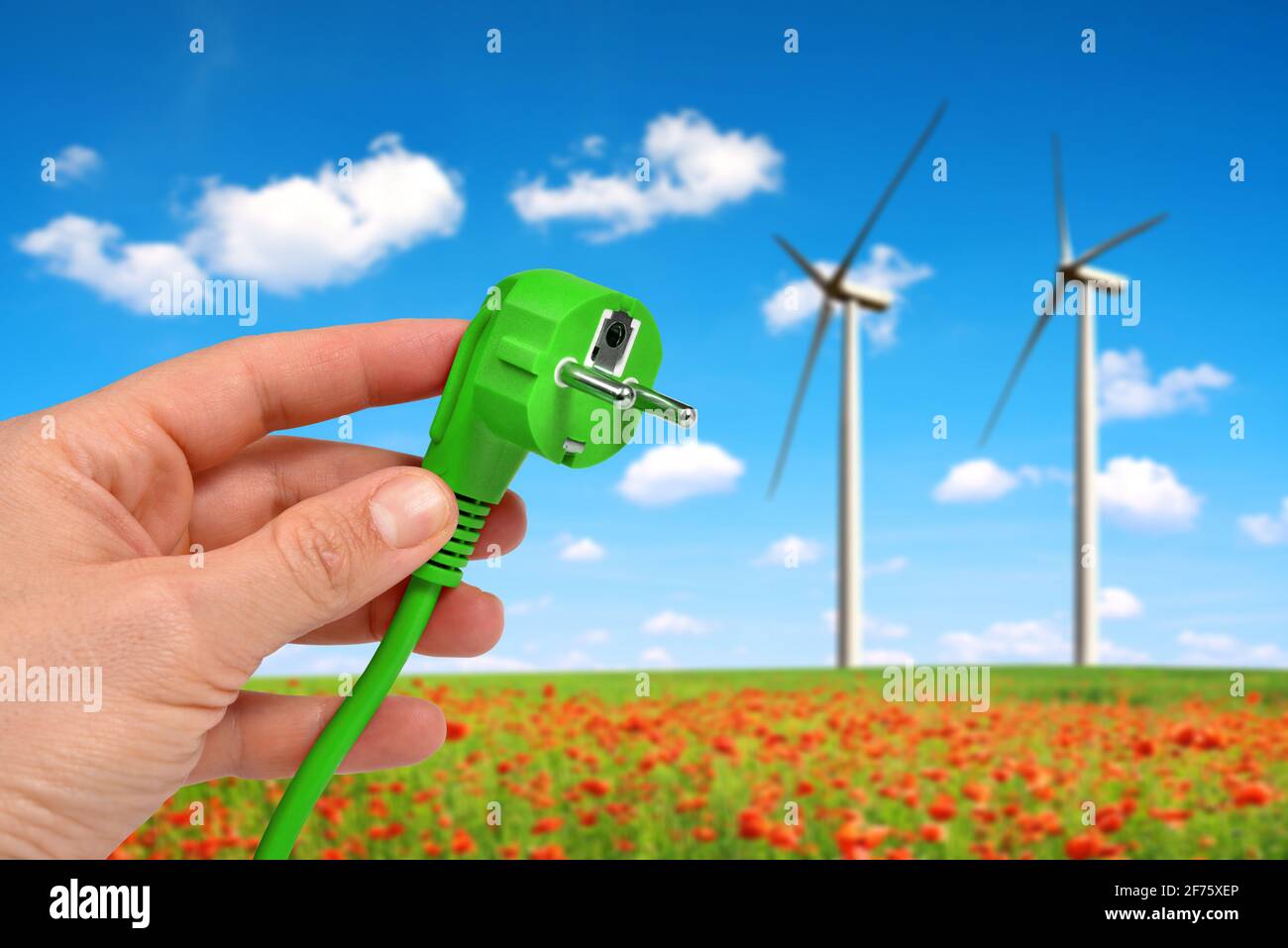 Hand holding green electric plug in the background wind turbines. Green ...