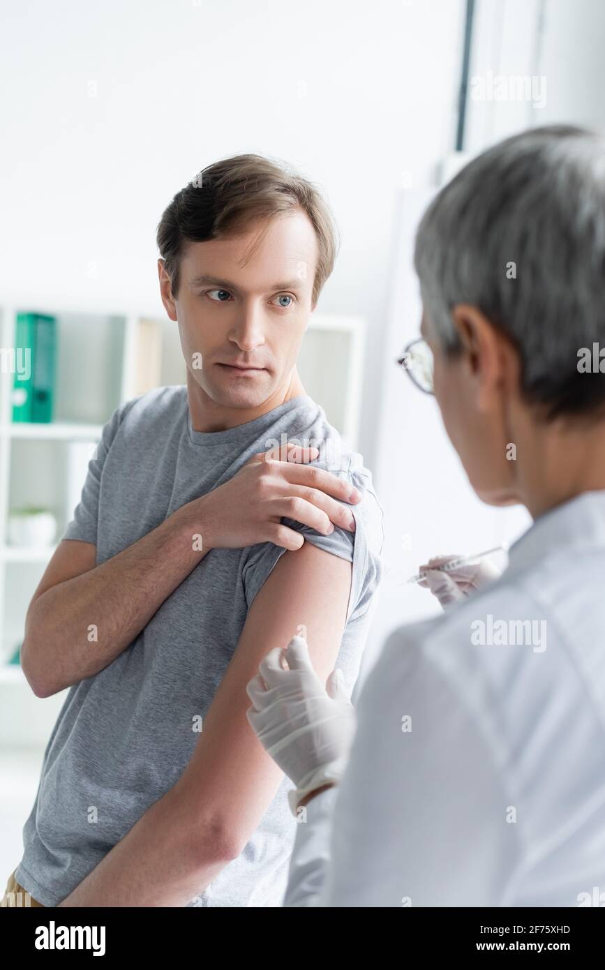 Patient looking at doctor with syringe during vaccination Stock Photo ...