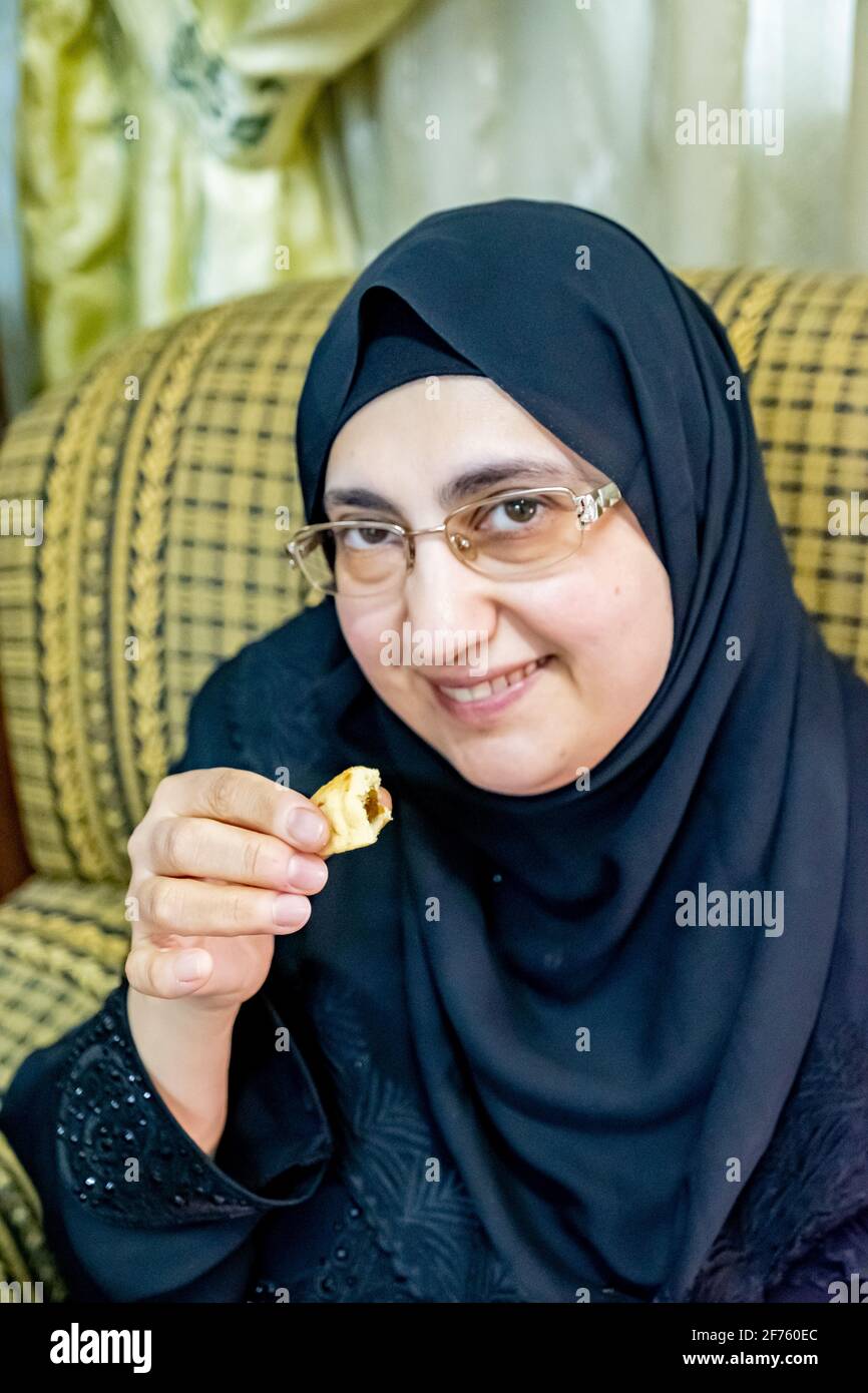 Arabic woman eating eid sweets Stock Photo - Alamy