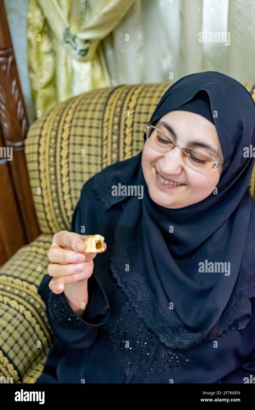 Arabic woman eating eid sweets Stock Photo - Alamy
