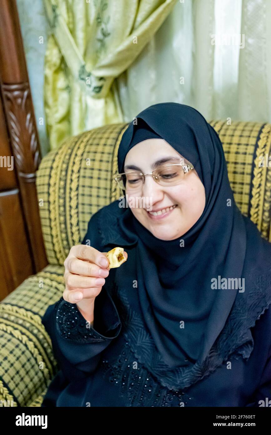 Arabic woman eating eid sweets Stock Photo - Alamy