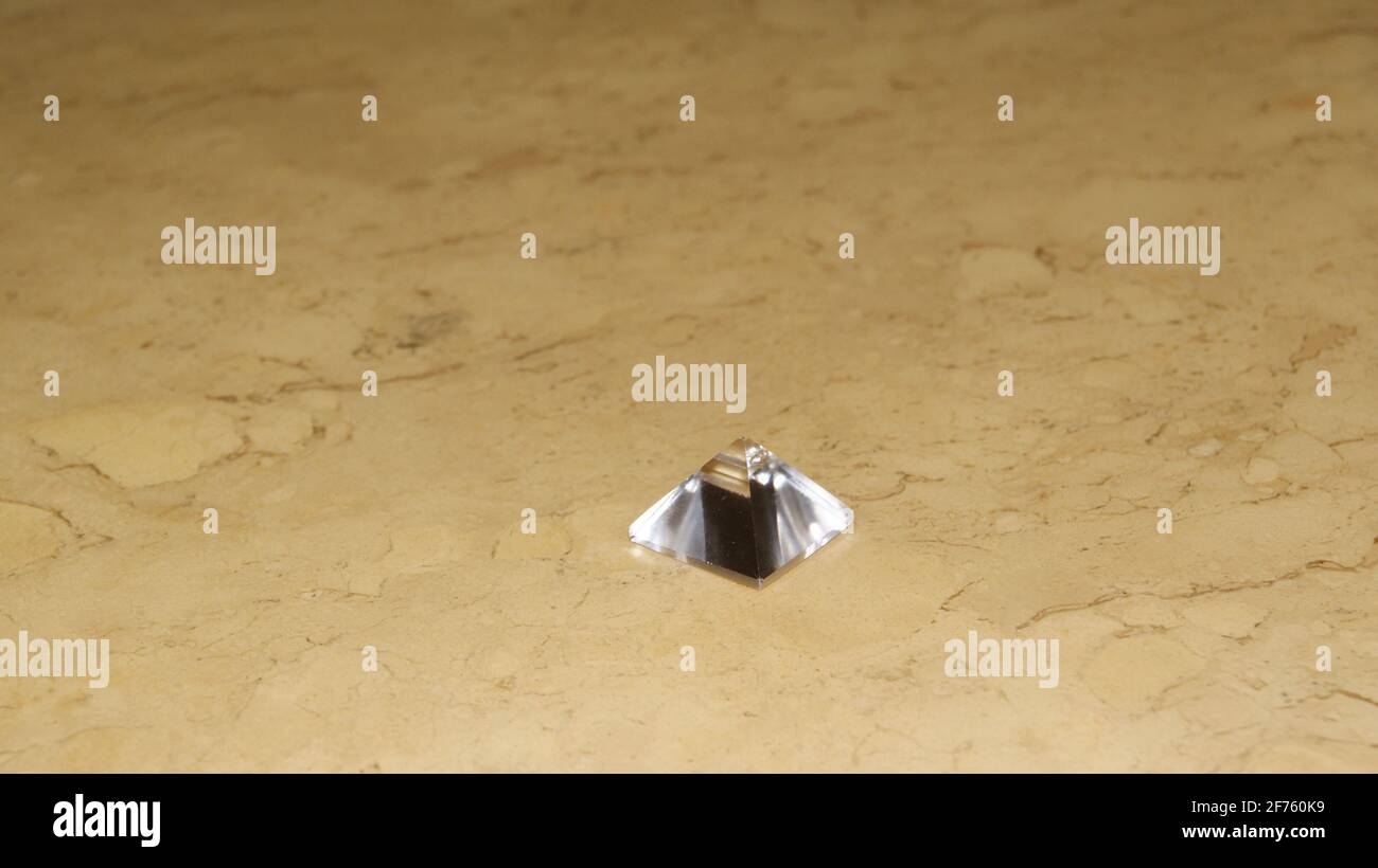 Pyramid. Crystal pyramid on travertine marble background in top-down ...