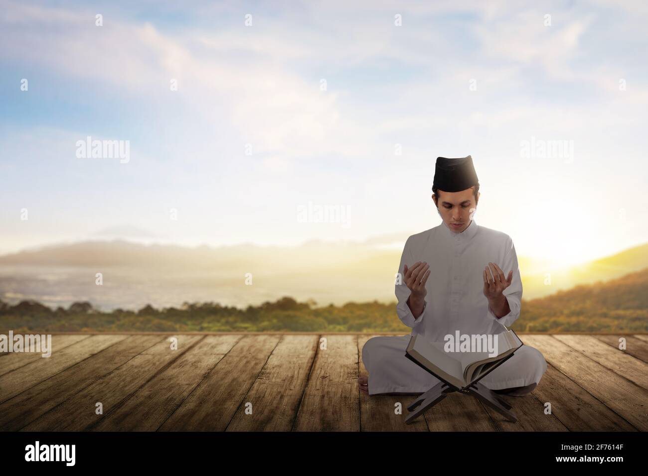 Asian Muslim man sitting while raised hands and praying on the wooden ...