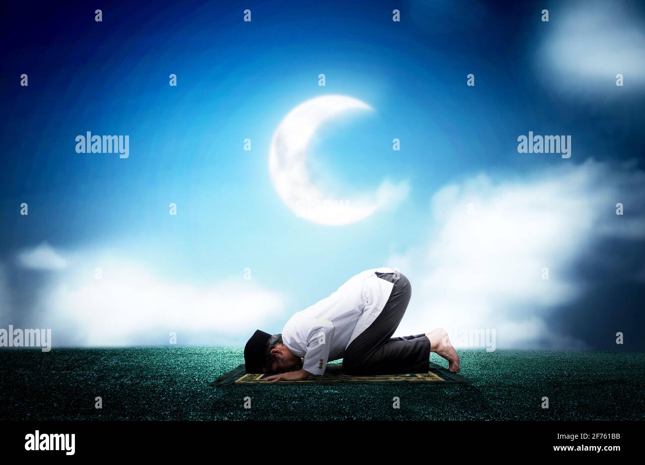 Asian Muslim man in praying position (salat) on prayer rug with ...