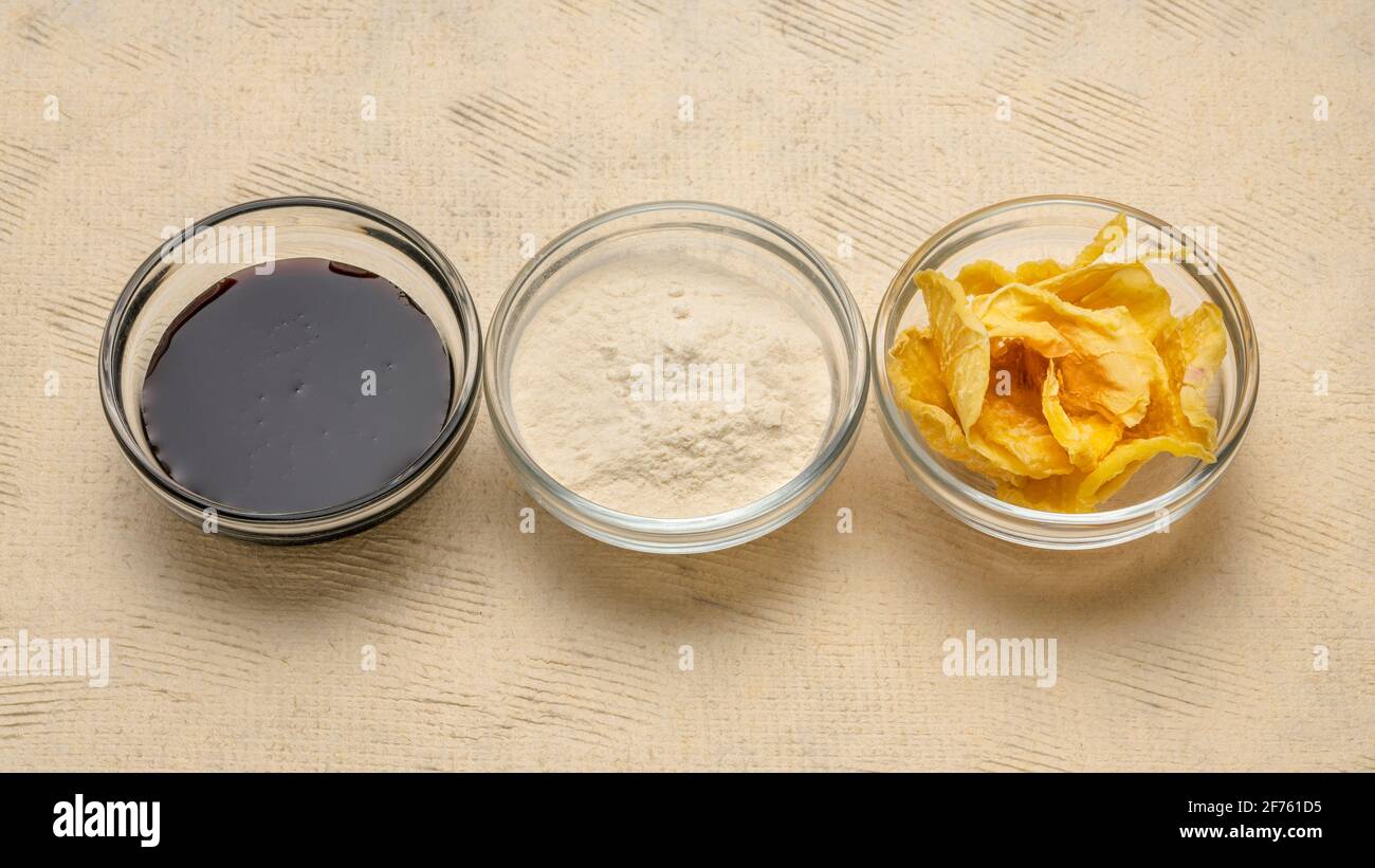 Dried slices of yacon tuber, syrup and powder in small glass bowls ...
