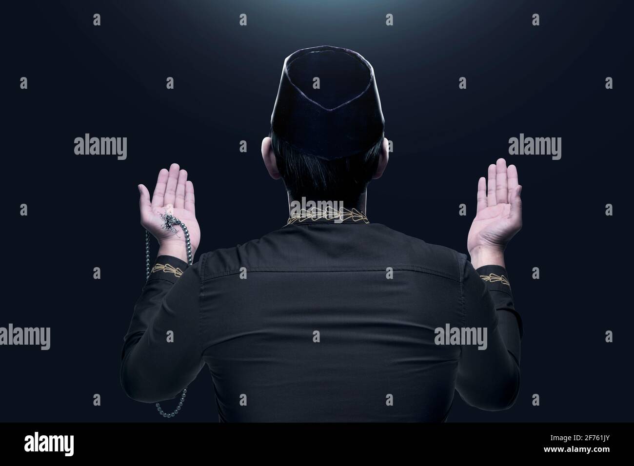 Rear view of Asian Muslim man praying with prayer beads on his hands ...