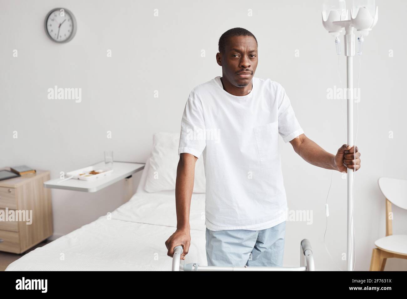 Waist up portrait of African-American man in hospital holding onto iv ...