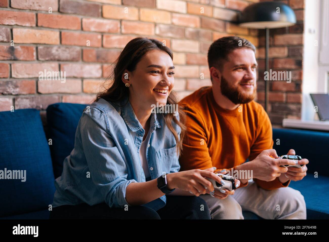 Happy cheerful young couple holding controllers and playing video games ...