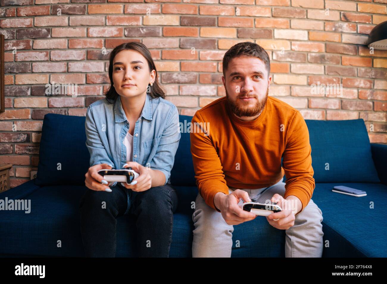 Portrait of happy young couple holding controllers and playing video ...