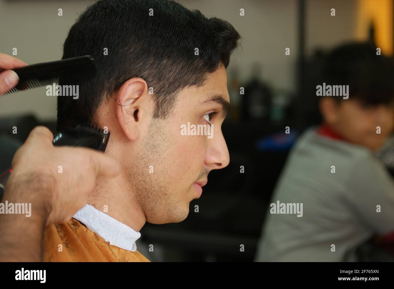 Barber trimming hair of man with clipper in barber shop Stock Photo - Alamy