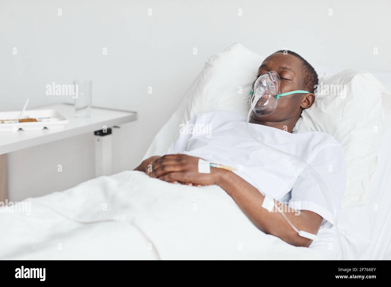 Portrait of African-American man in hospital bed with oxygen mask and ...