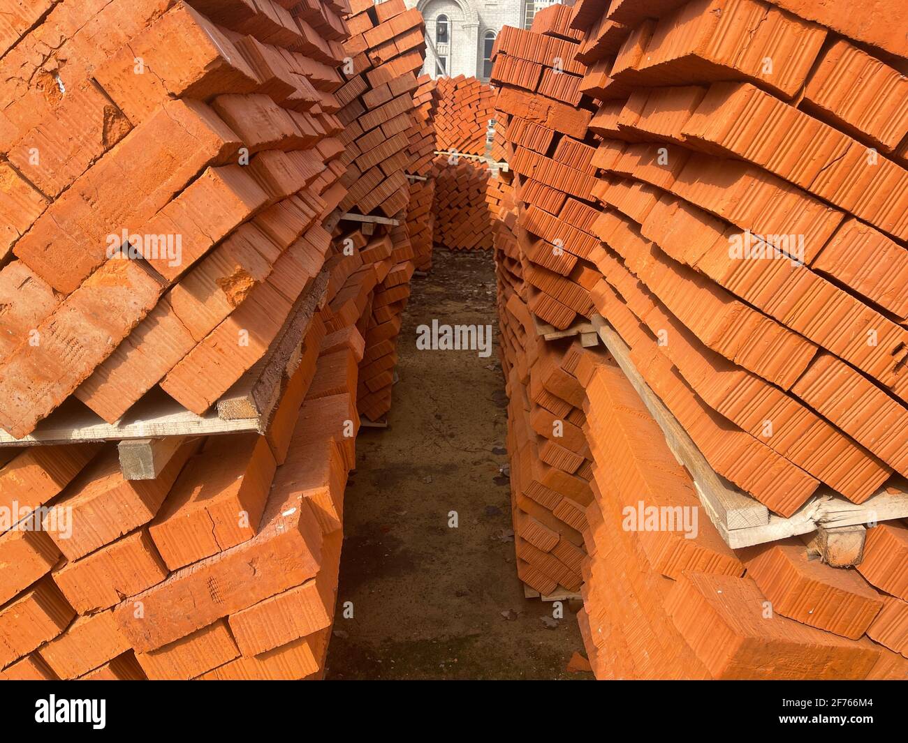 Pile of pallets with red bricks on city street. Building materials on ...