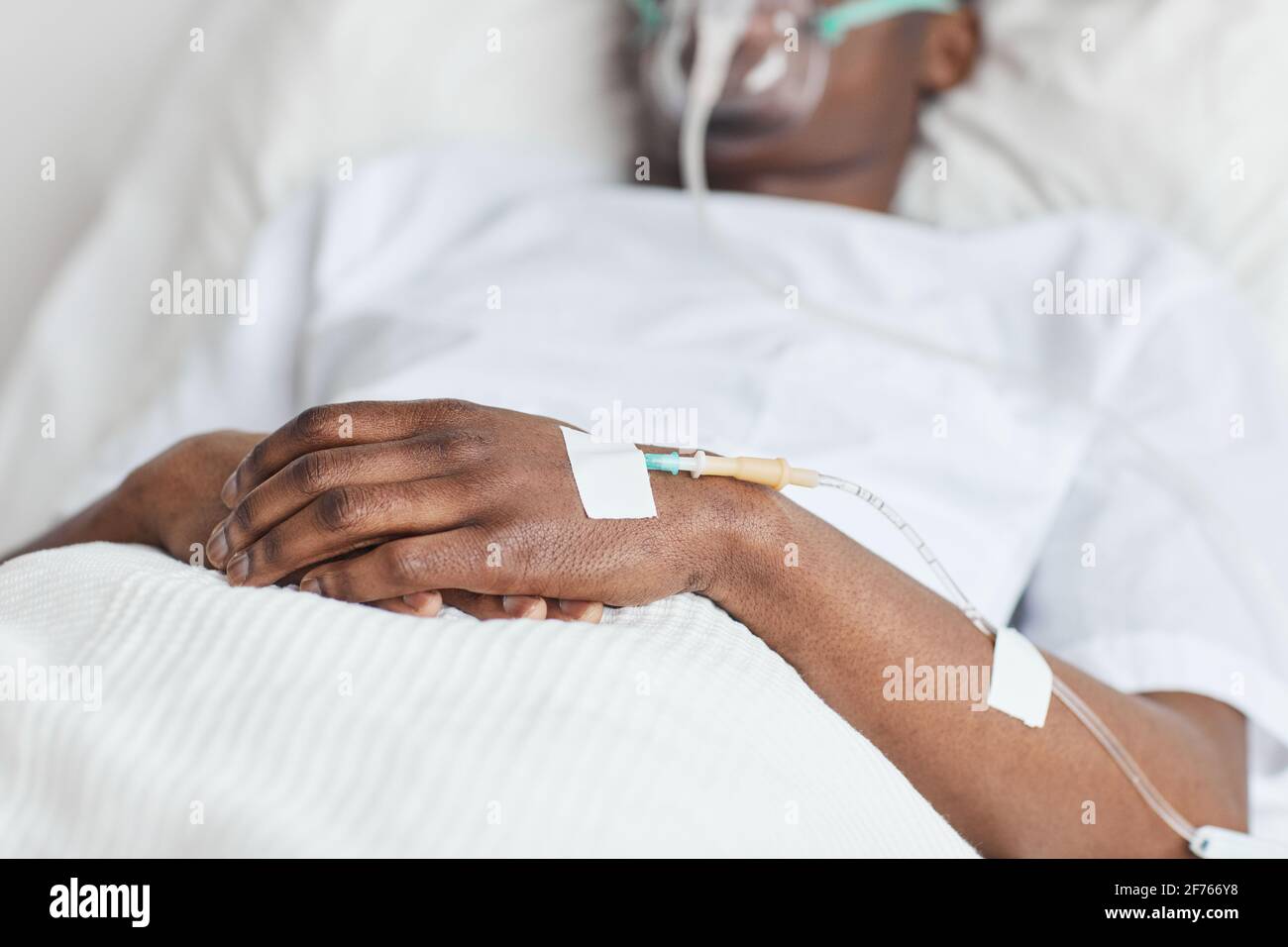 Close up of unrecognizable African-American man lying in white hospital ...