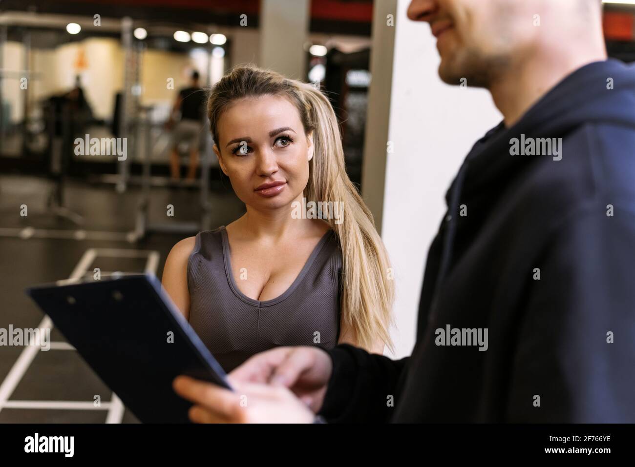 Woman and personal trainer writing exercise plan in gym. fitness, sport ...