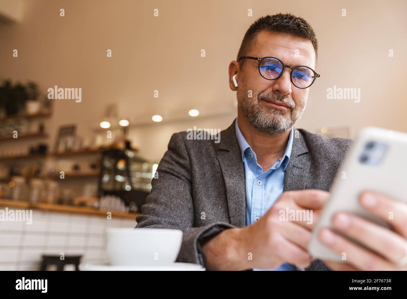 Young man texting message on smart phone while listening to music on ...
