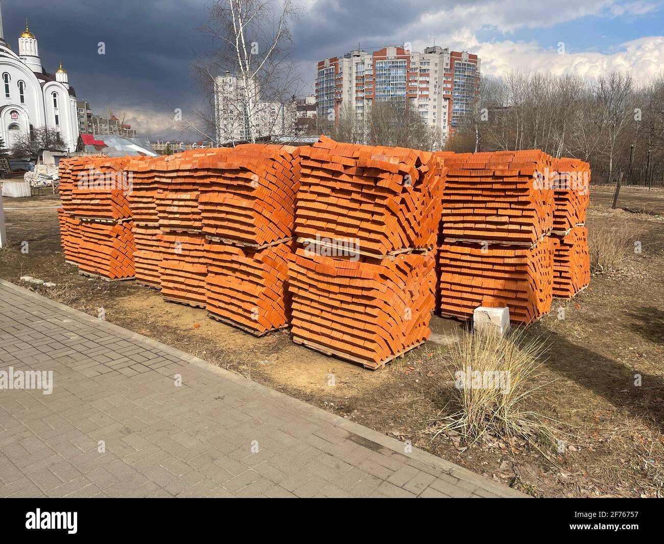 Pile of pallets with red bricks on city street. Building materials on ...